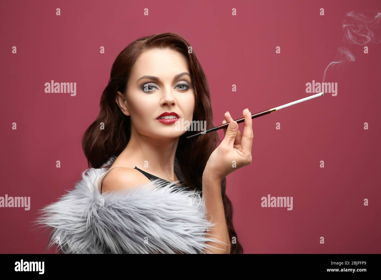 Beautiful woman smoking cigar on color background Stock Photo - Alamy