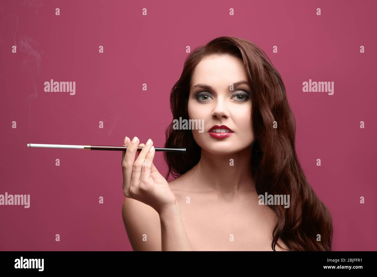 Beautiful woman smoking cigar on color background Stock Photo - Alamy