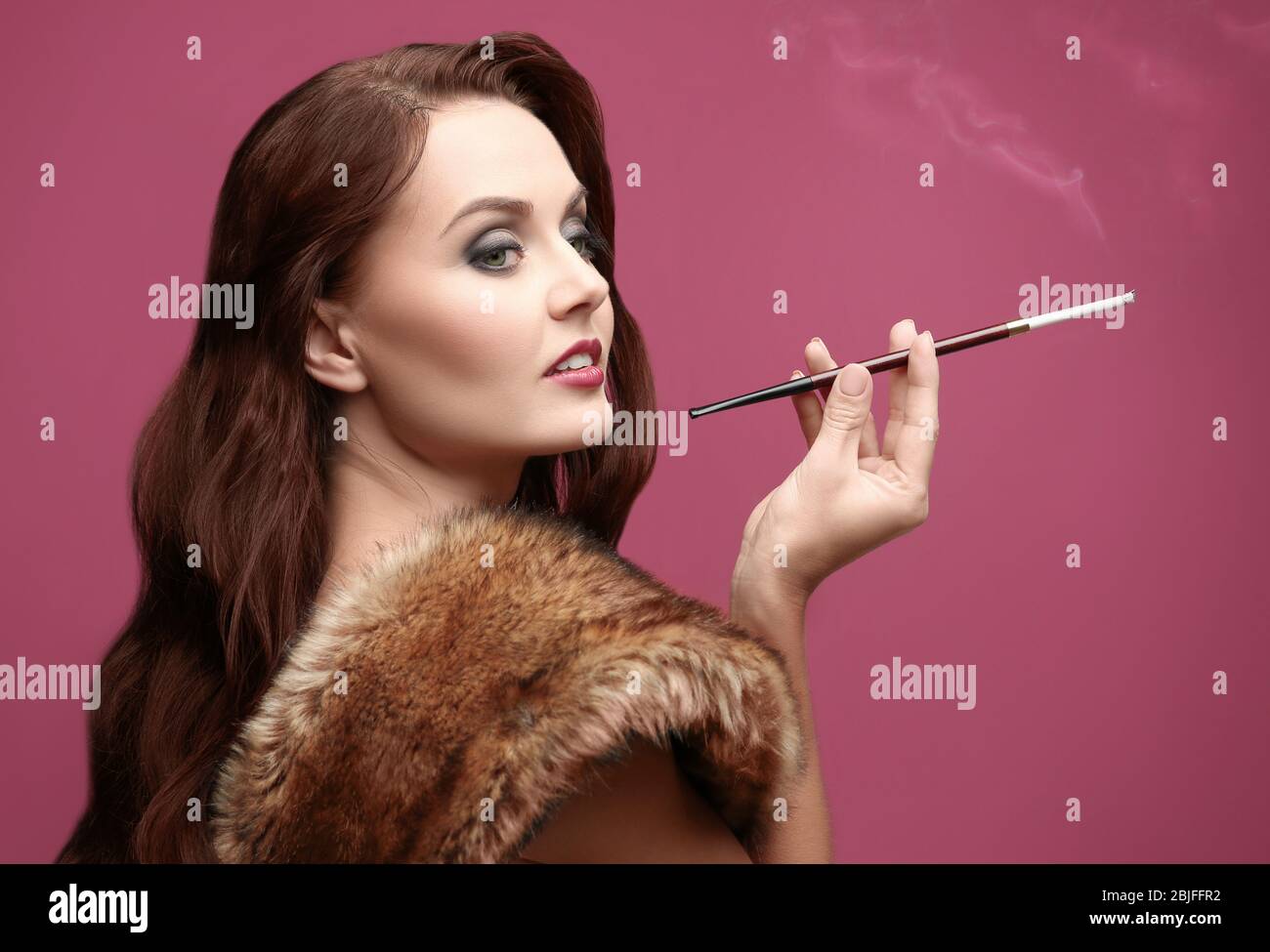 Beautiful woman smoking cigar on color background Stock Photo - Alamy