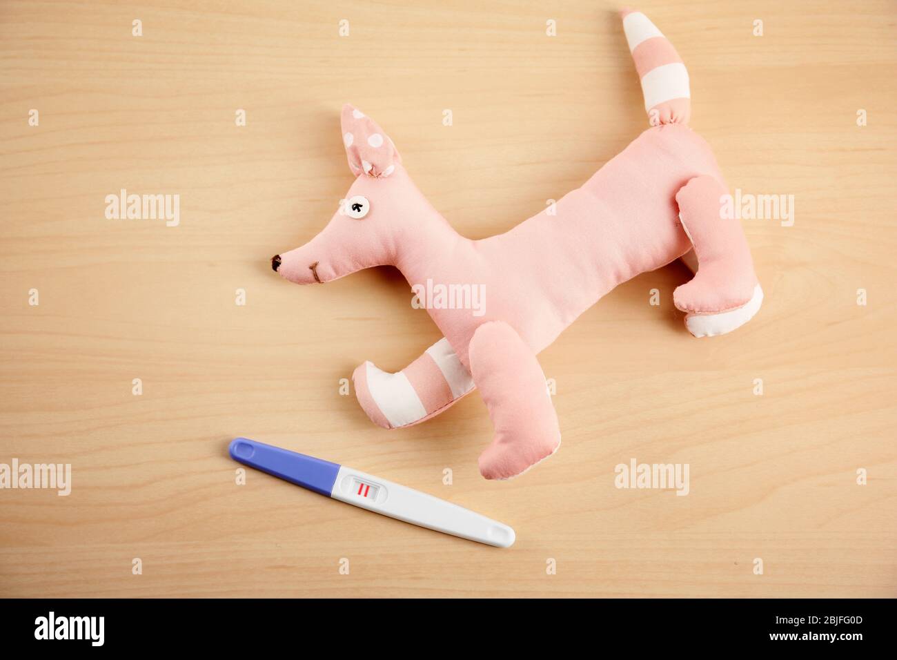 Pregnancy test and cute textile toy on wooden background Stock Photo ...