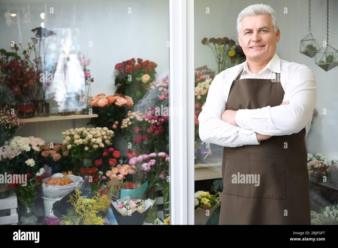 Male florist standing against showcase in flower shop Stock Photo - Alamy