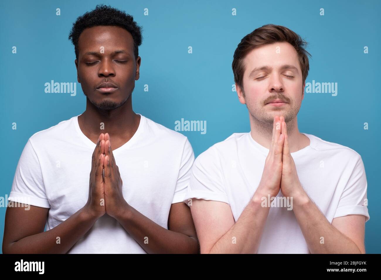 Hopeful adult men closing eyes and pressing palms together, praying ...
