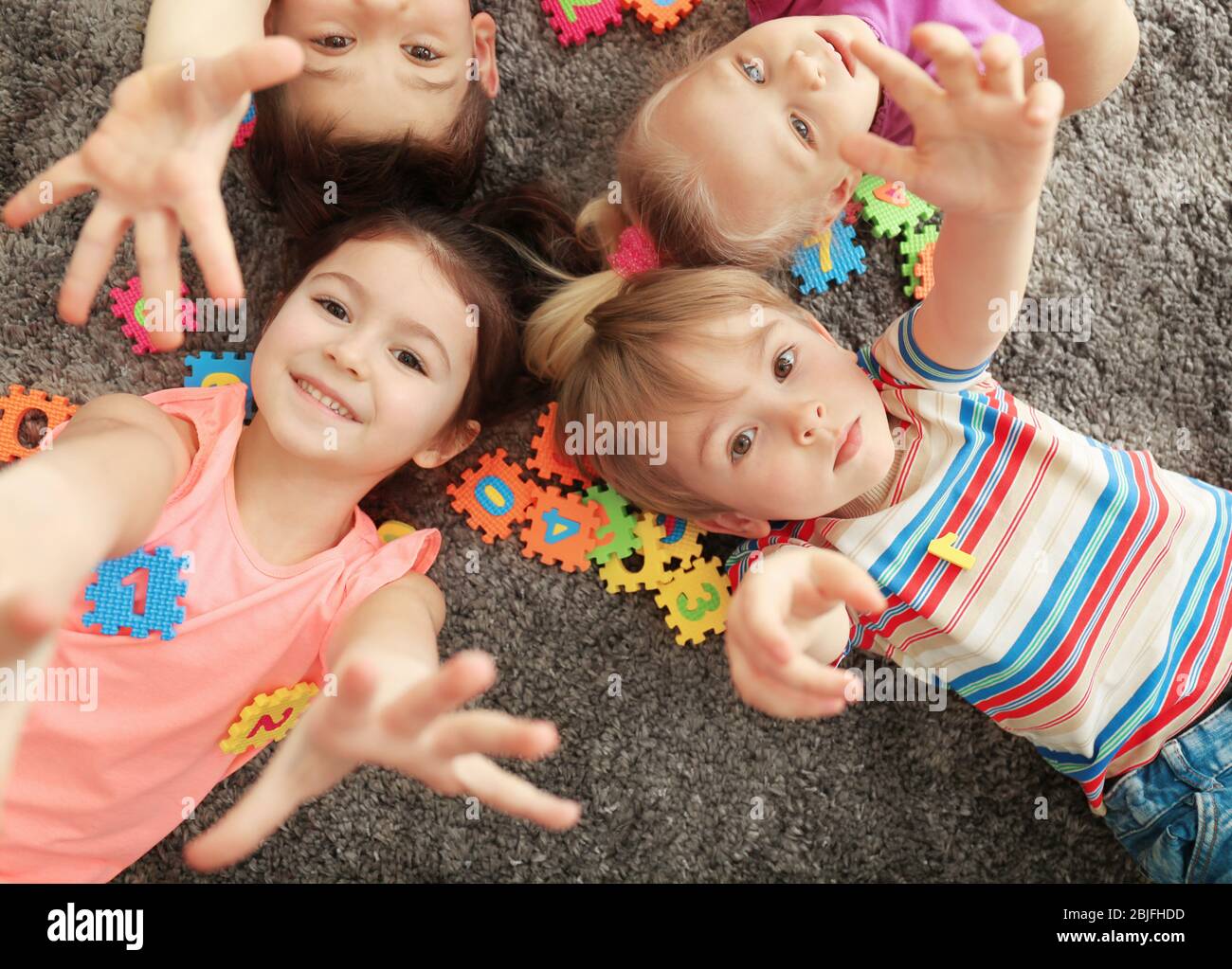 Cute little children playing with colorful figures while lying on ...