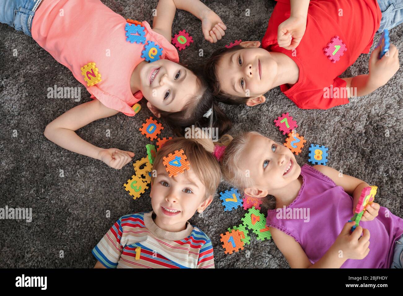 Cute little children playing with colorful figures while lying on ...
