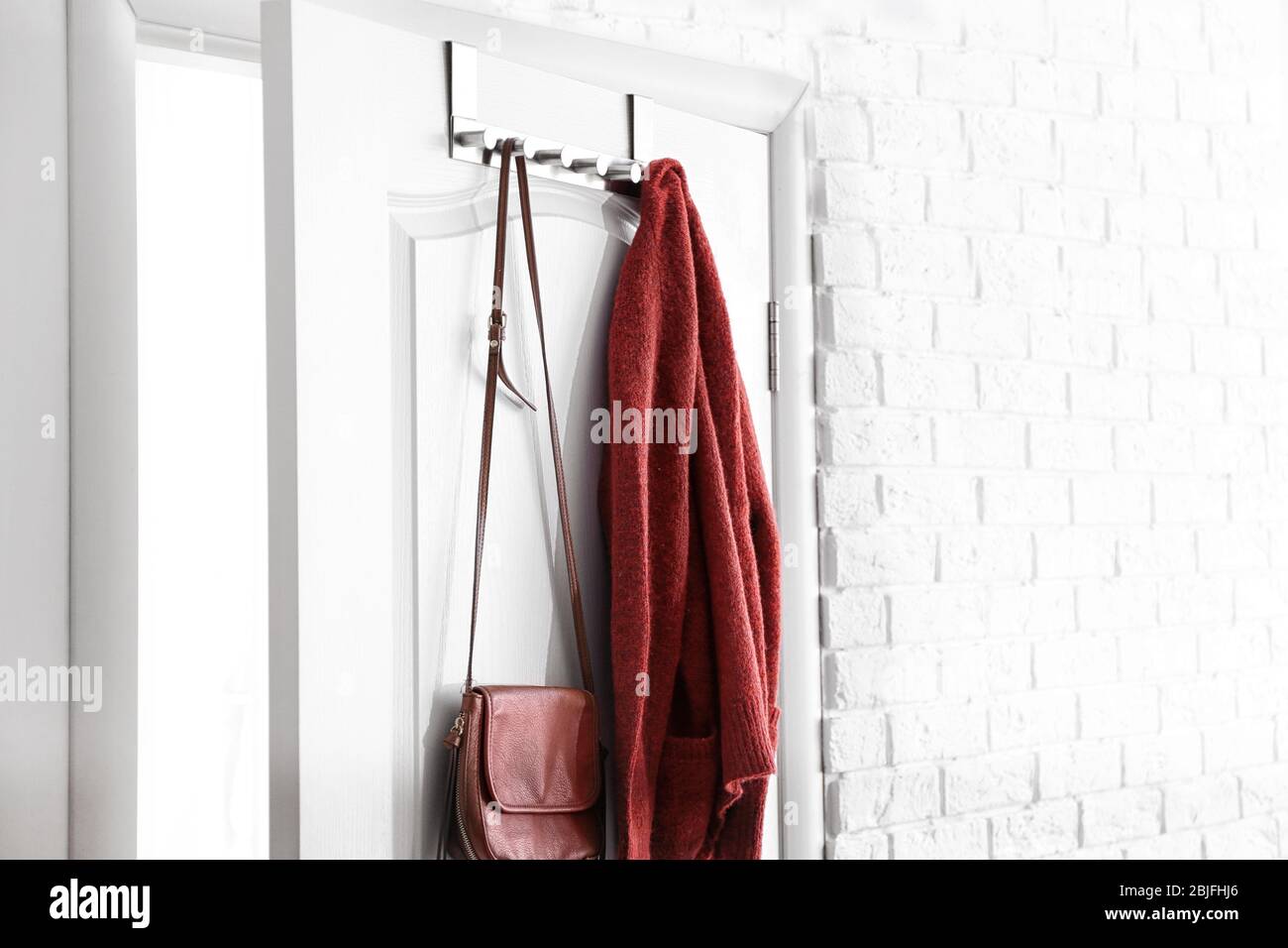 Hanging clothes on door in modern hall interior Stock Photo - Alamy