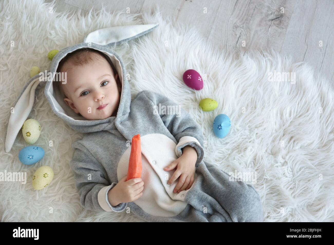 Cute little baby in bunny costume lying on furry rug Stock Photo - Alamy