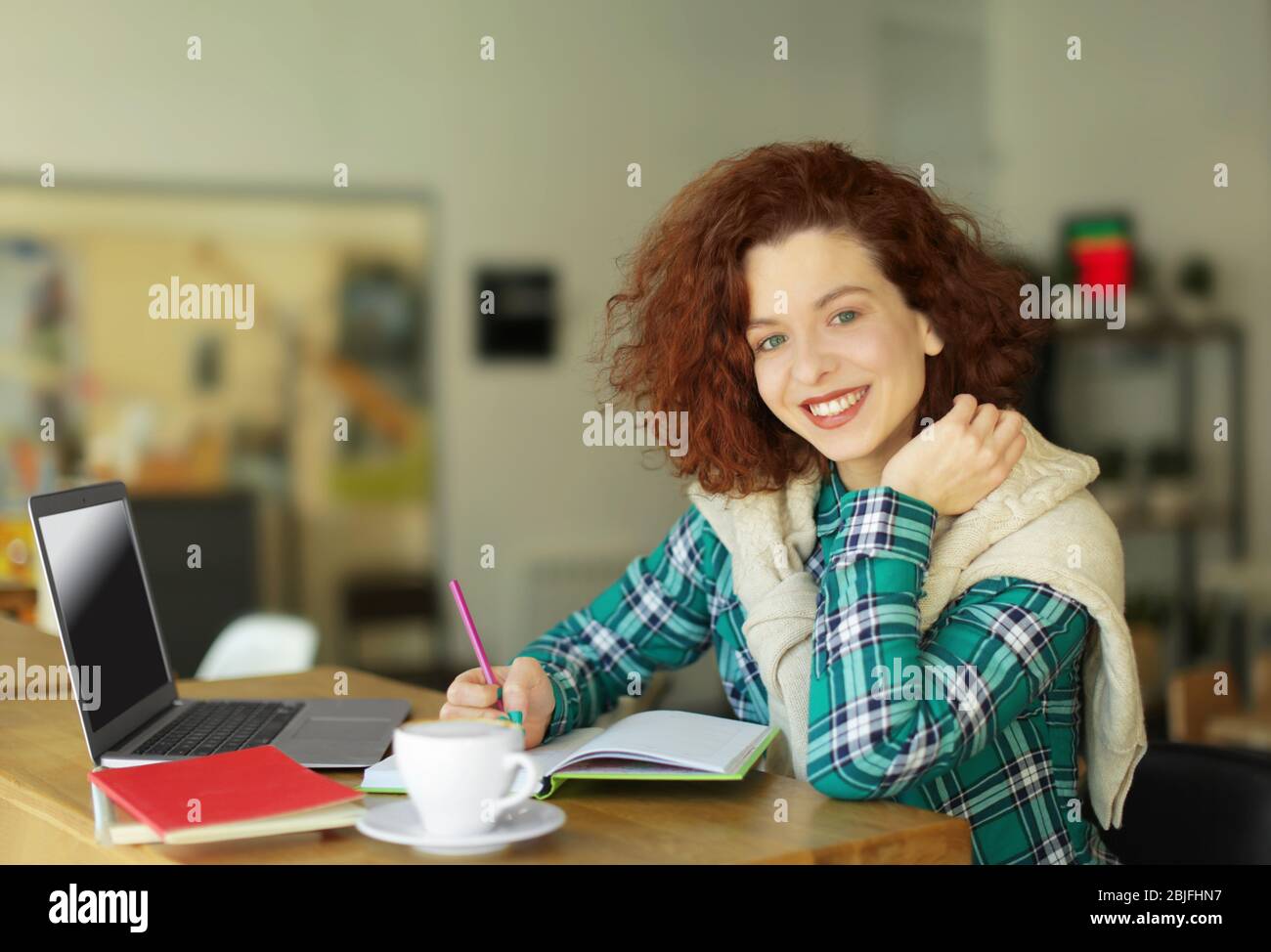 Beautiful girl writing in notebook in cafe Stock Photo - Alamy