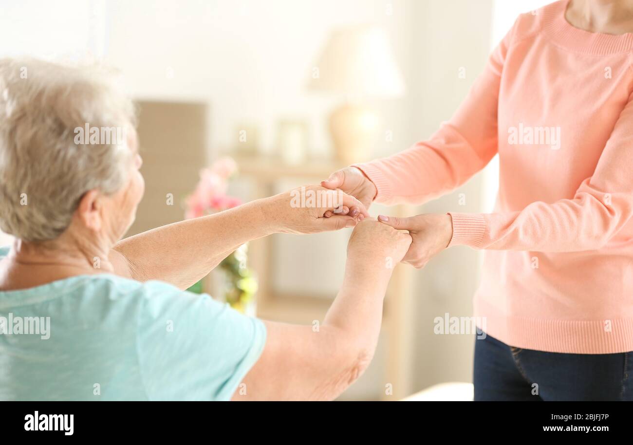 Old and young women holding hands on blurred background Stock Photo - Alamy