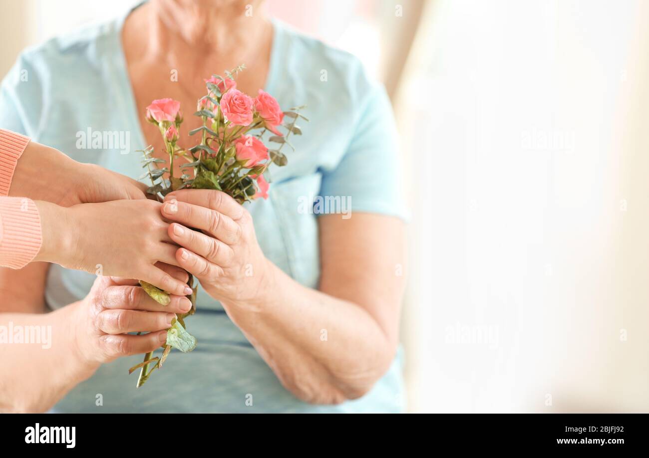 Female hands giving flowers to old woman Stock Photo - Alamy