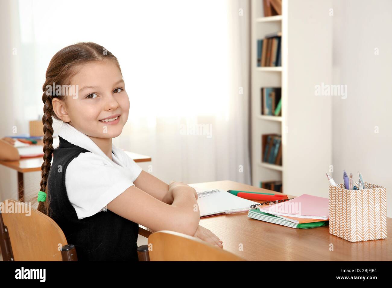 Beautiful elementary schoolgirl studying in classroom Stock Photo - Alamy