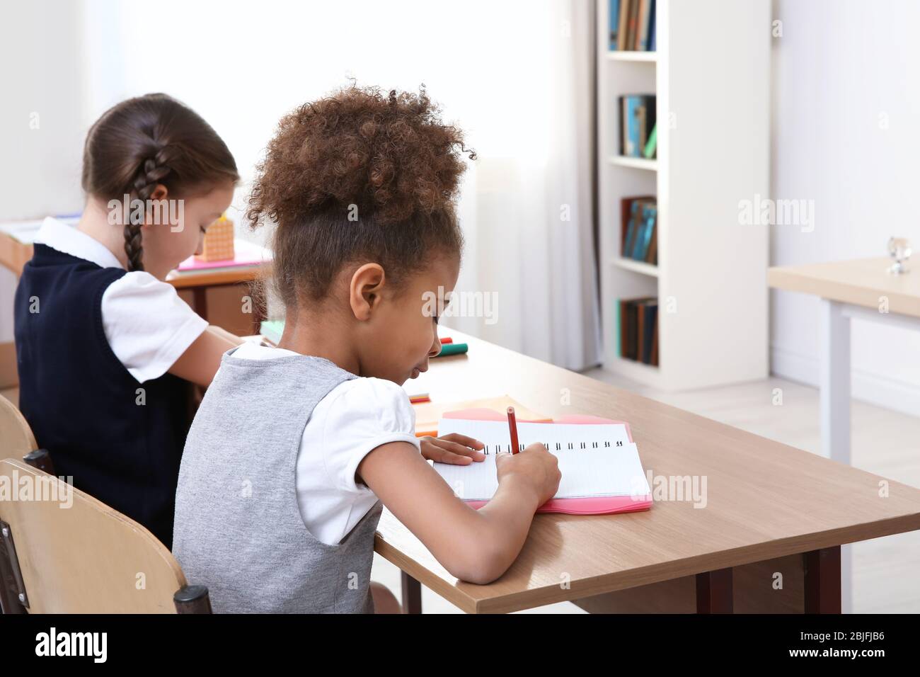 Beautiful elementary schoolgirls studying in classroom Stock Photo - Alamy