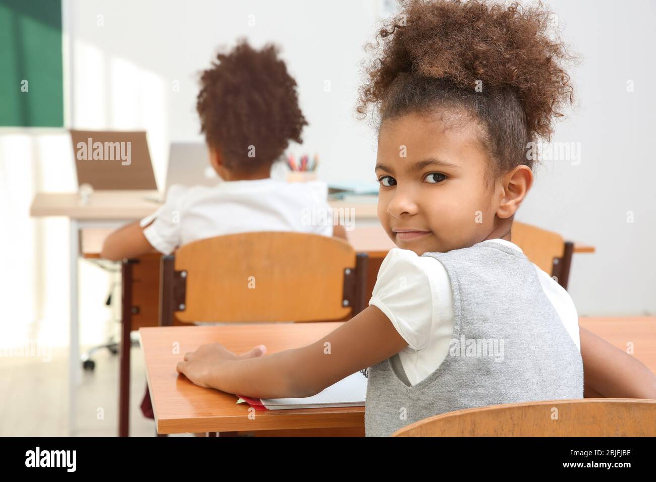 Beautiful elementary schoolgirl studying in classroom Stock Photo - Alamy