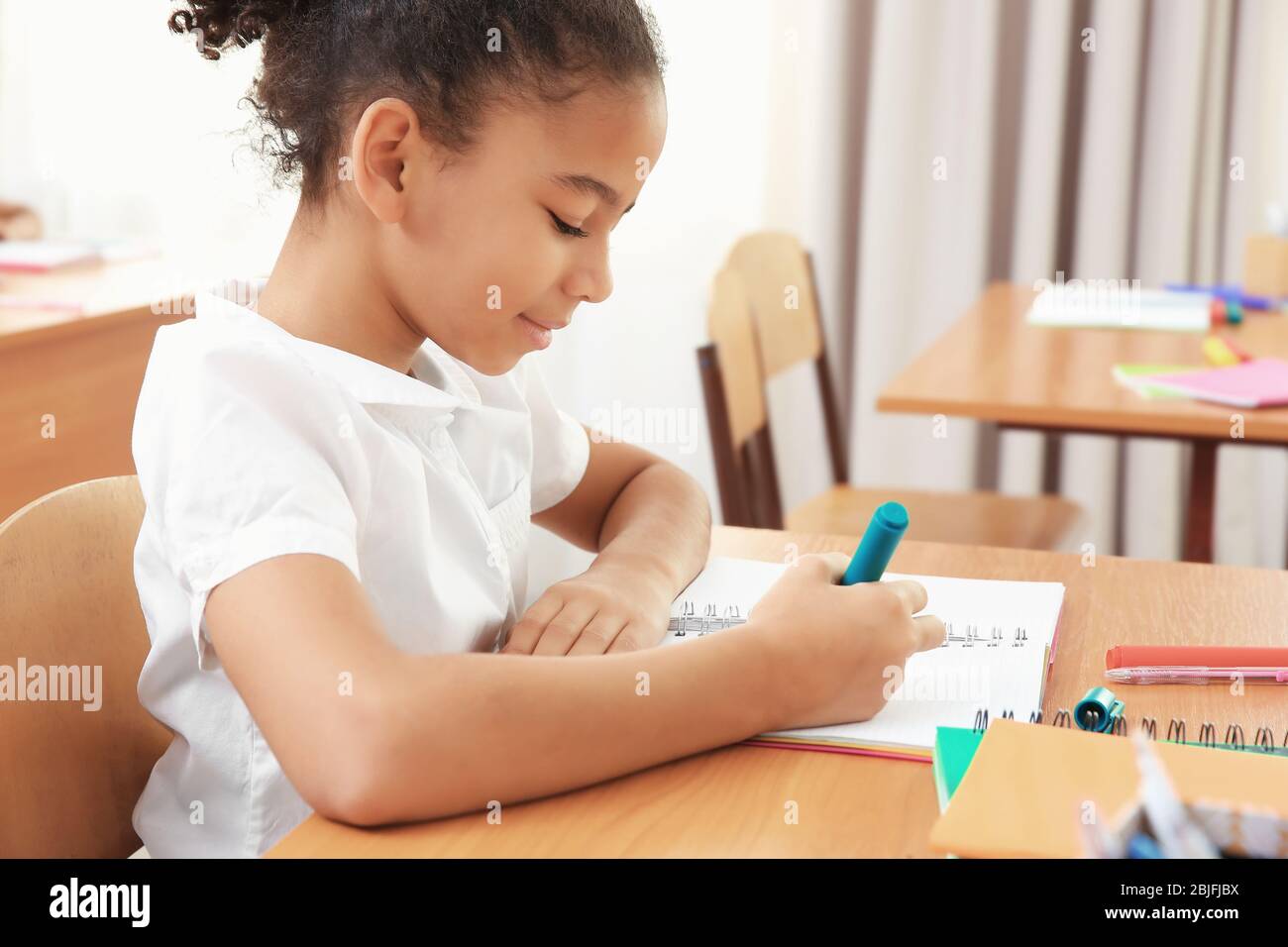 Beautiful elementary schoolgirl studying in classroom Stock Photo - Alamy