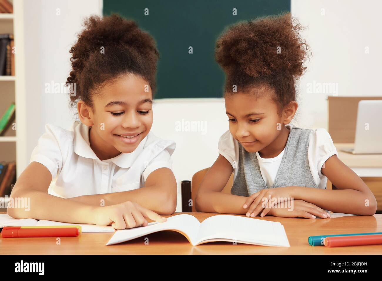 Beautiful elementary schoolgirls studying in classroom Stock Photo - Alamy