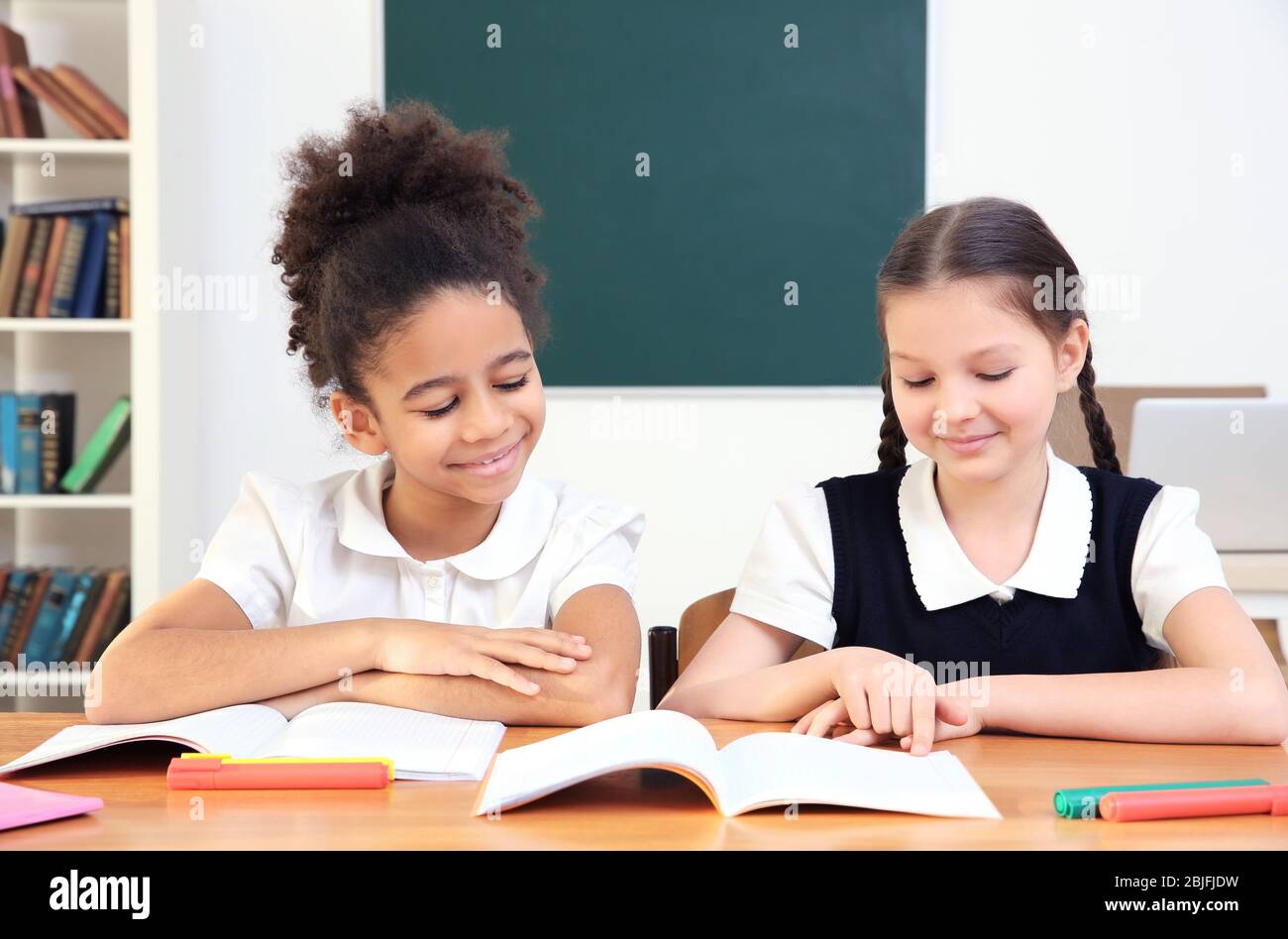 Beautiful elementary schoolgirls studying in classroom Stock Photo - Alamy