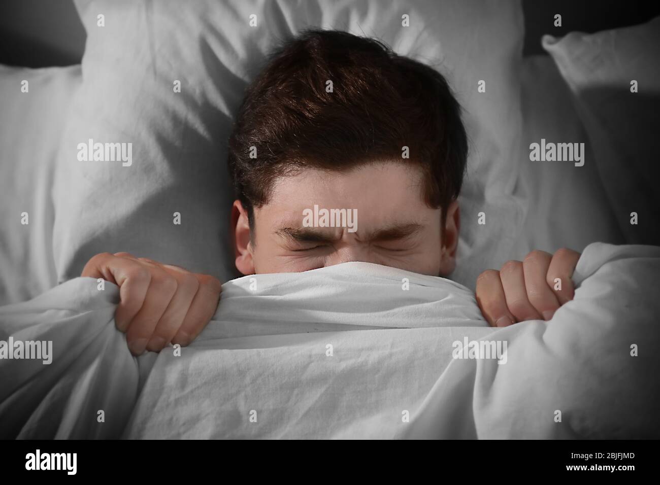 Young scared man lying in bed at home Stock Photo - Alamy