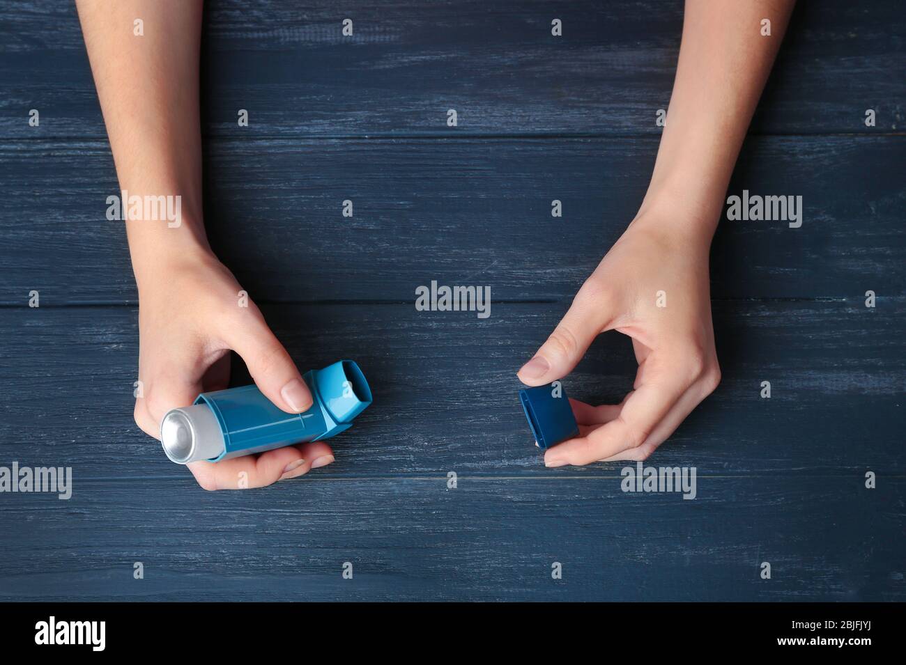 Female hands holding asthma inhaler on wooden background Stock Photo ...