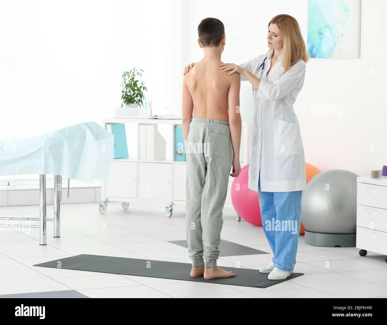 Incorrect posture concept. Physiotherapist examining and correcting boy ...