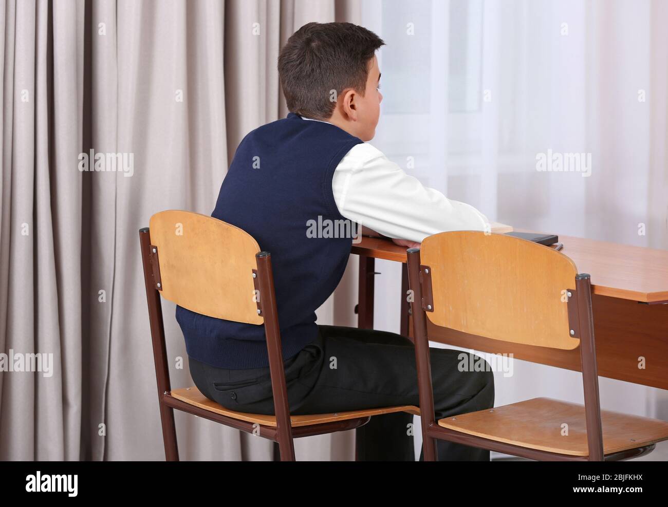 Incorrect posture concept. Schoolboy sitting at desk in classroom Stock ...