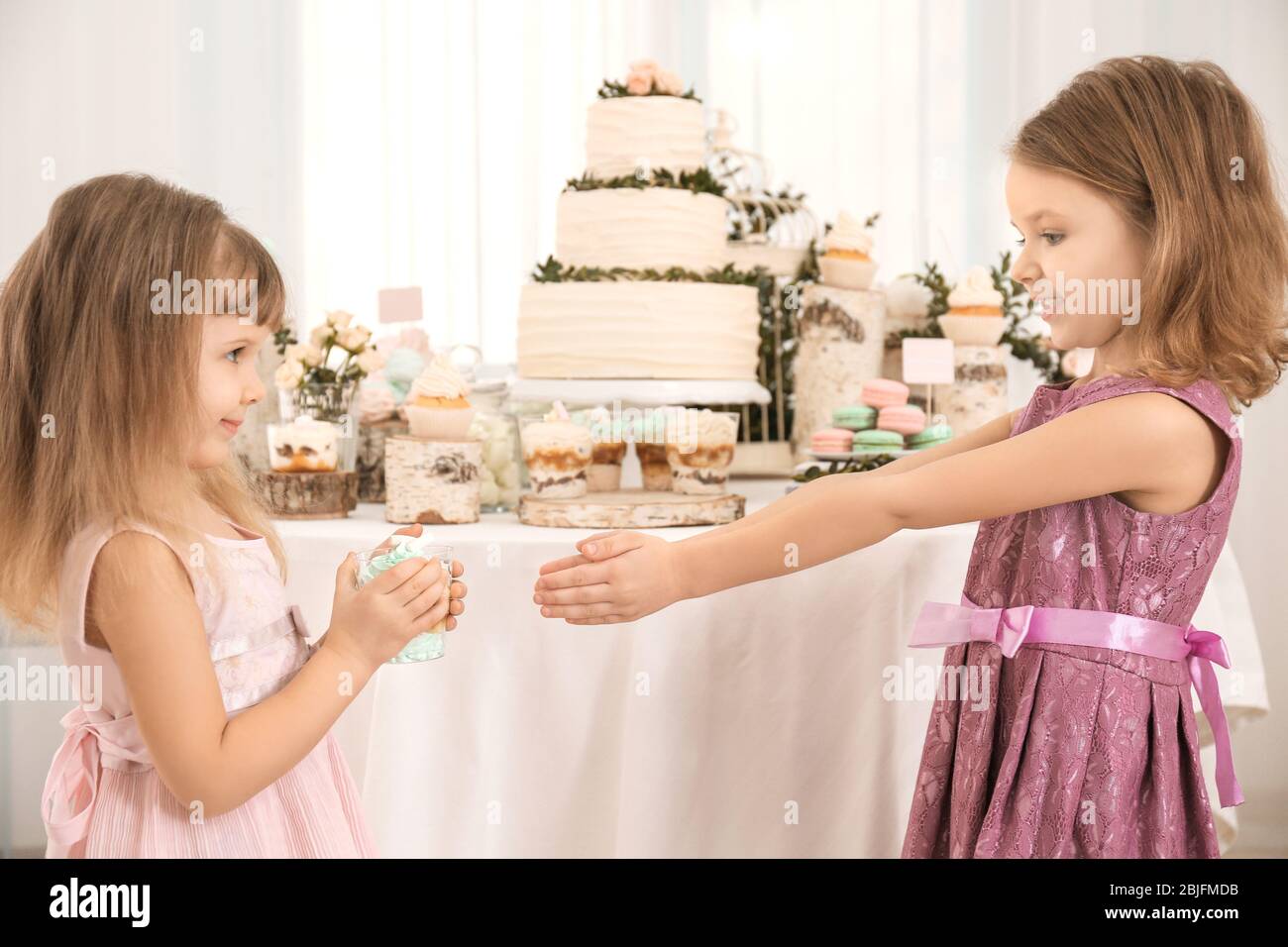 Cute girl giving tasty dessert to her friend at party Stock Photo - Alamy