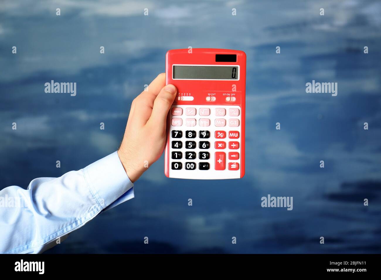 Male hand holding calculator on color background. Tax concept Stock ...