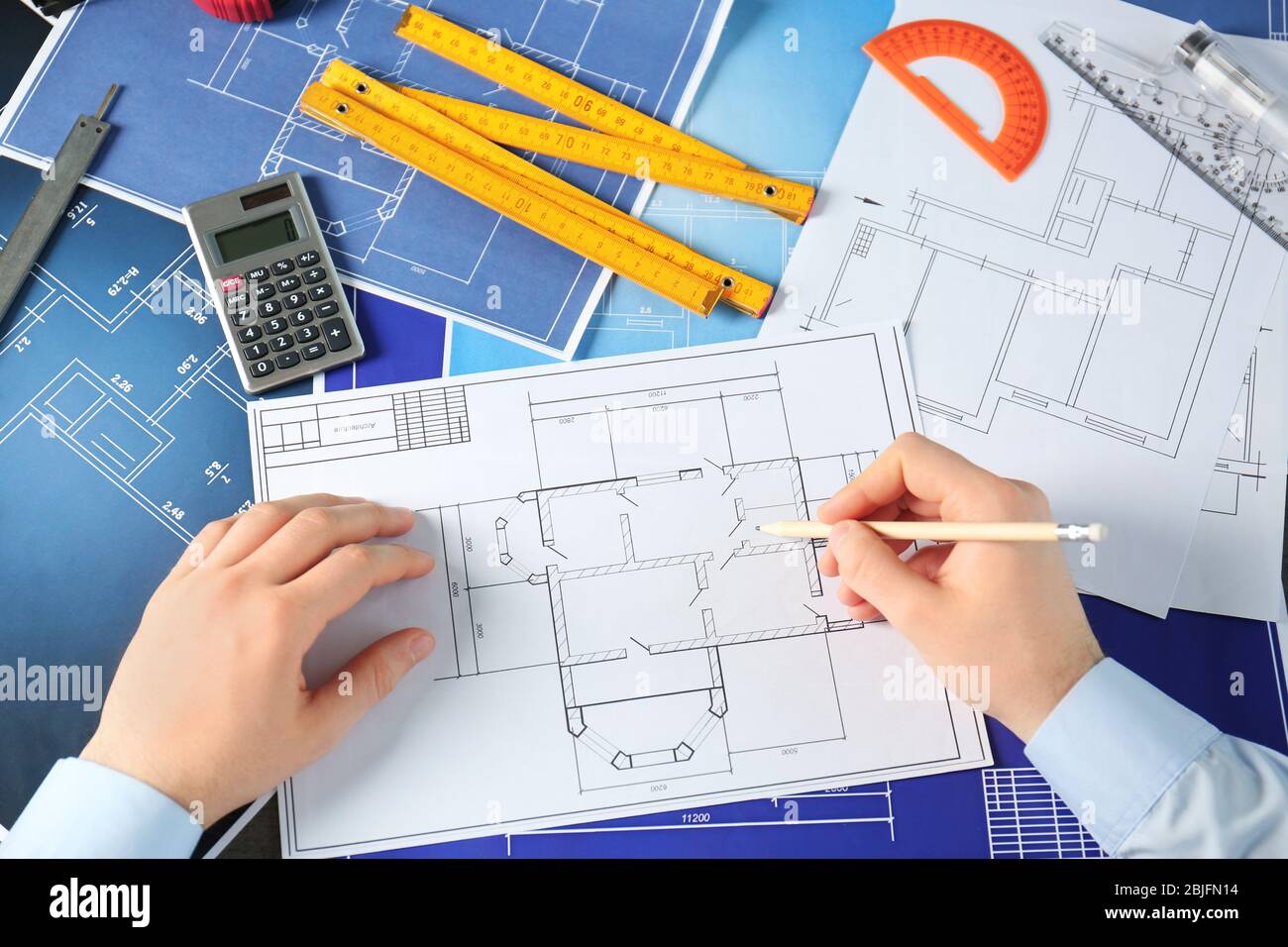 Male engineer hands working with blueprints on table Stock Photo - Alamy
