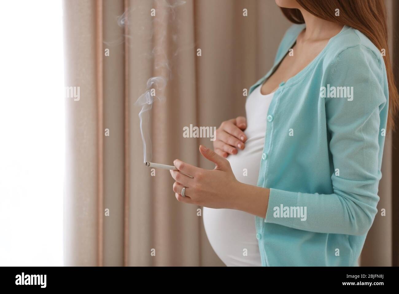 Woman smoking by window hi-res stock photography and images - Alamy