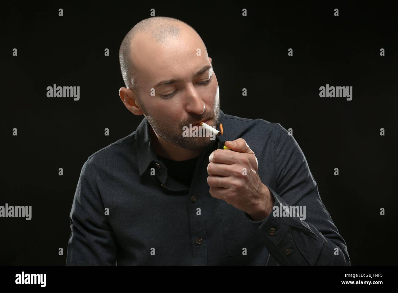 Handsome man smoking cigarette on dark background Stock Photo - Alamy