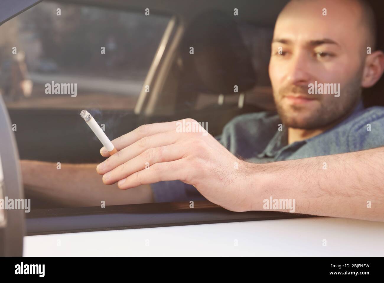 Handsome man smoking cigarette in car Stock Photo - Alamy