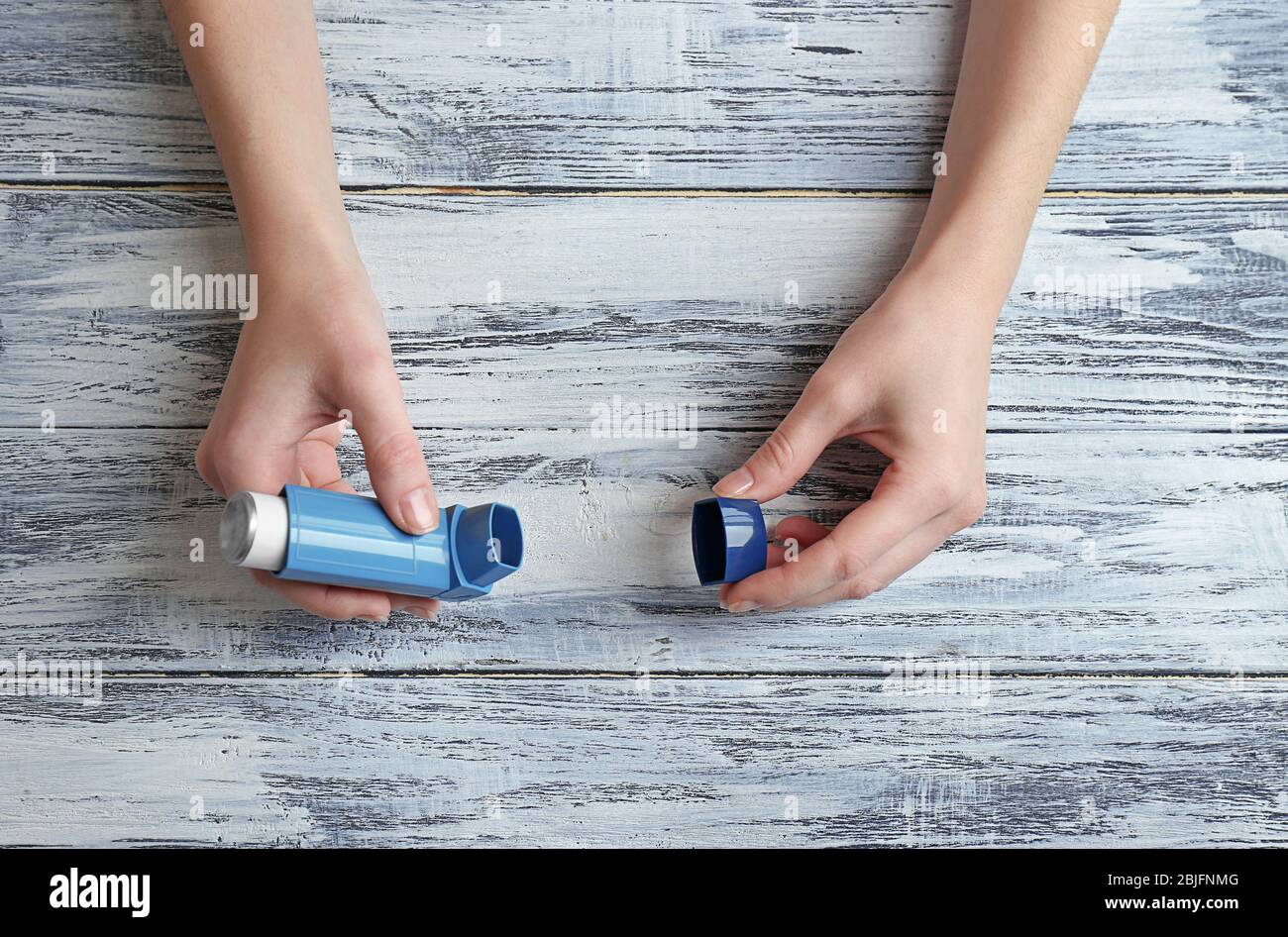 Female hands holding asthma inhaler on wooden background Stock Photo ...
