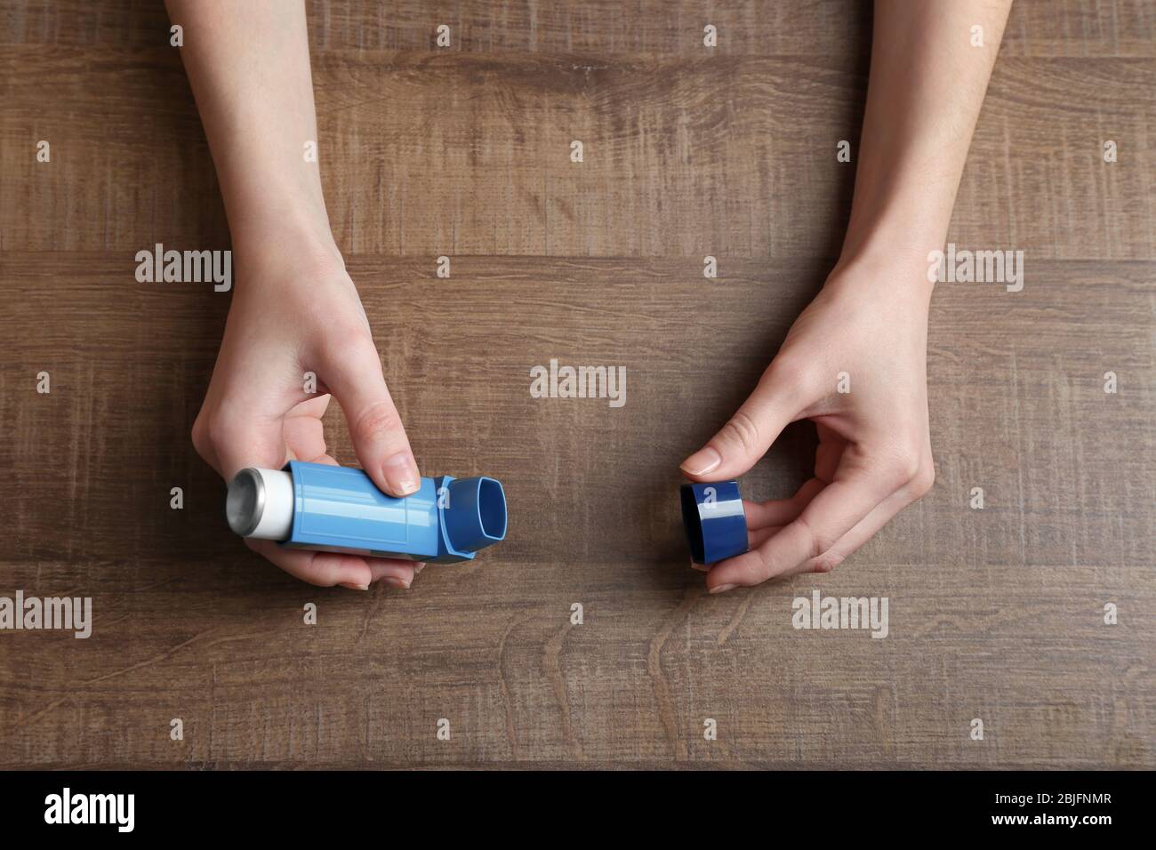 Female hands holding asthma inhaler on wooden background Stock Photo ...