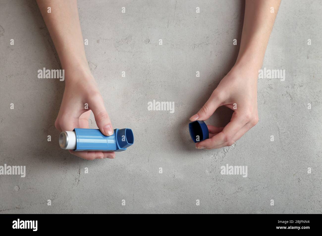 Female hands holding asthma inhaler on gray textured background Stock ...