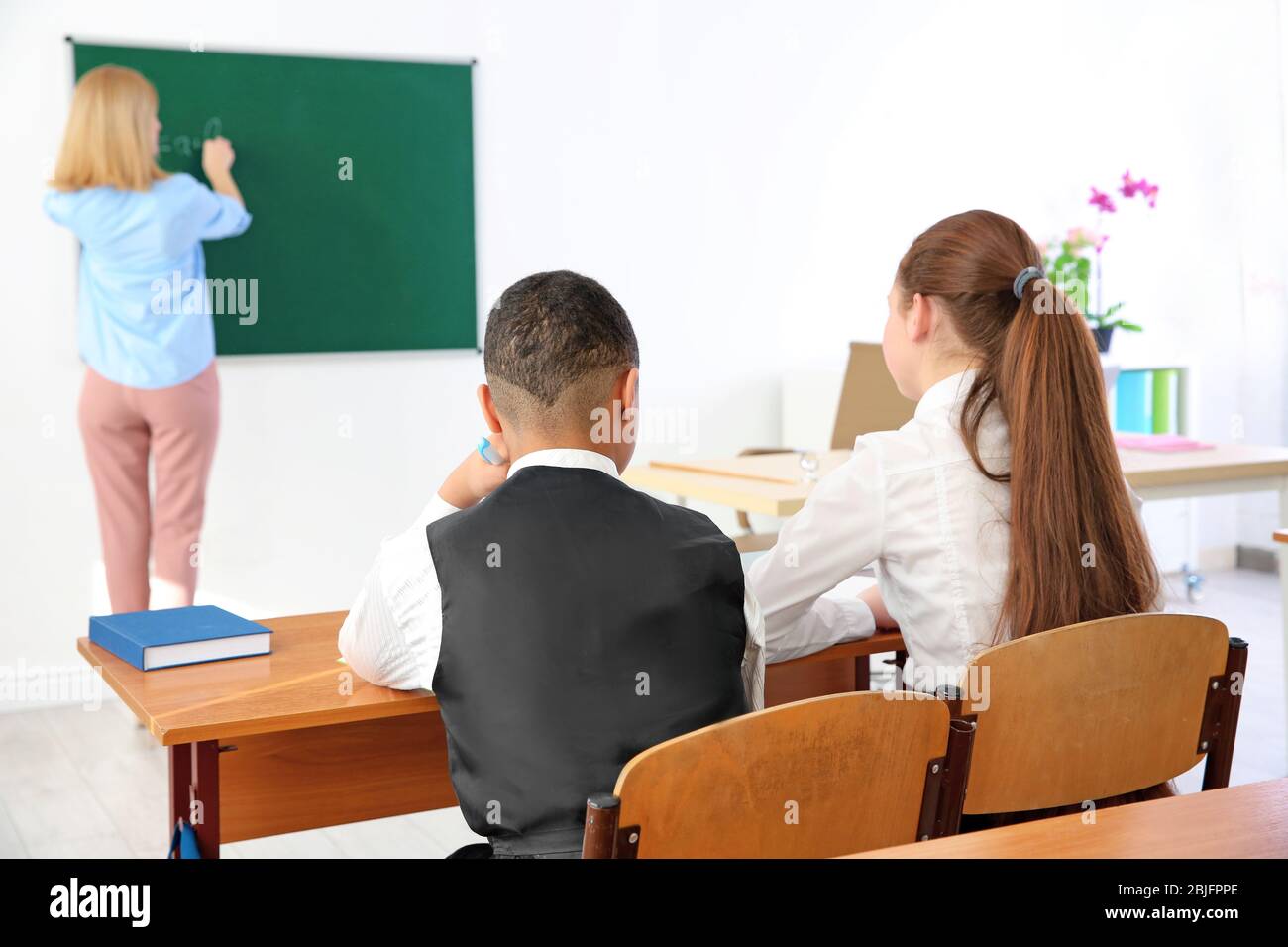 Pupils listening to teacher in classroom Stock Photo - Alamy