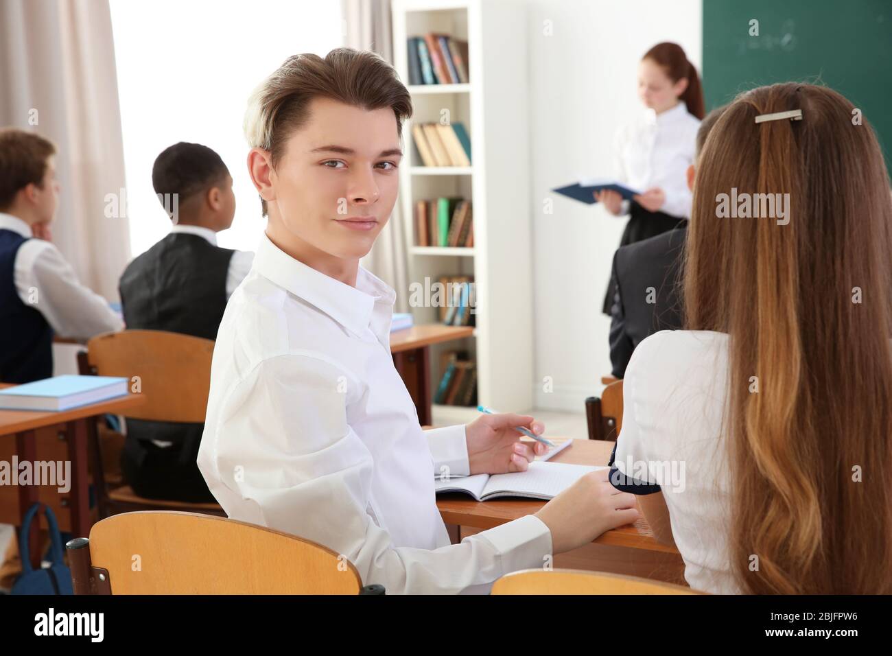 Cute teenage boy at lesson in classroom Stock Photo - Alamy