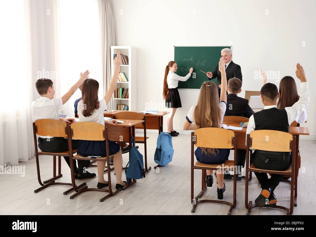 Teenagers in classroom raising hands hi-res stock photography and ...