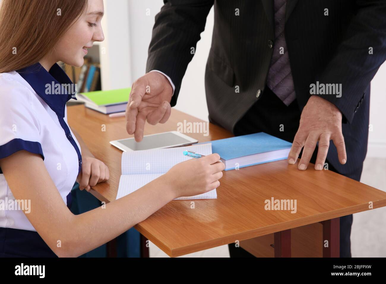 Senior teacher explaining exercise to schoolgirl in classroom Stock ...