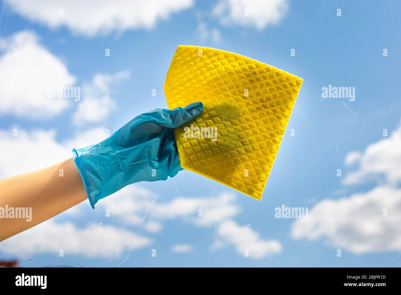 Human hand holding napkin for cleaning window on sky background Stock ...