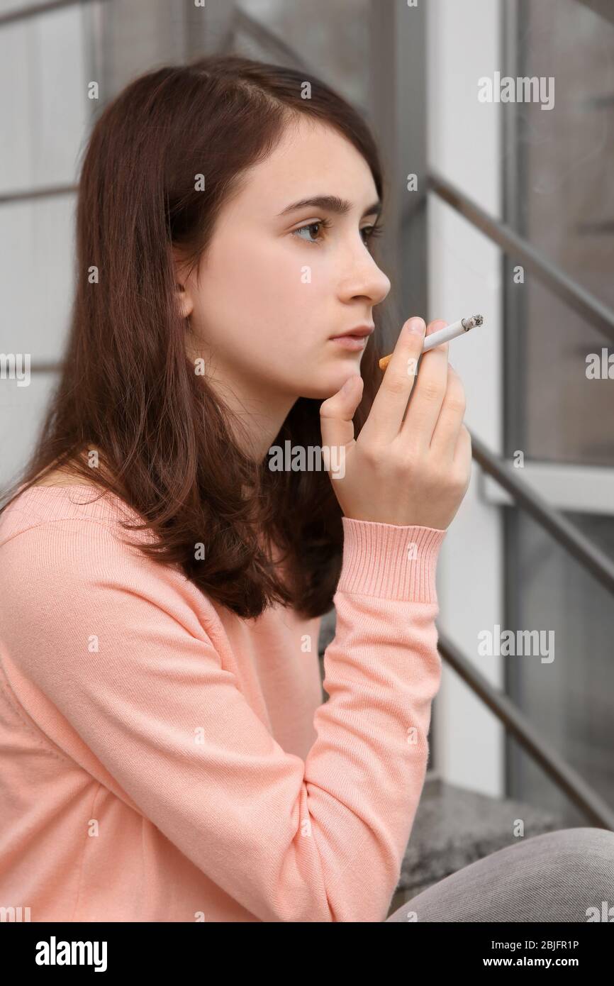 Teenage girl sitting on stairs and smoking Stock Photo - Alamy