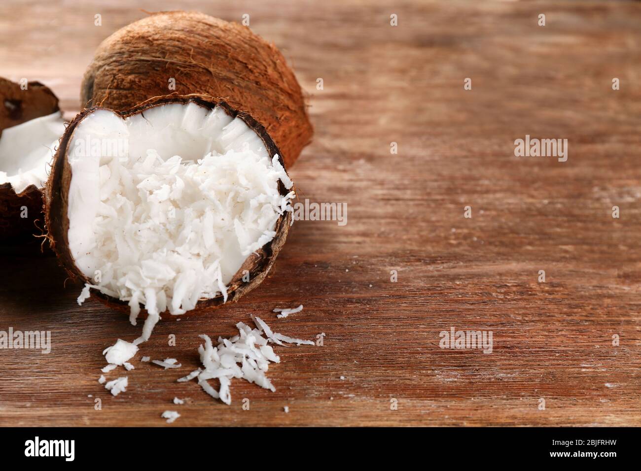Grated coconut in shell and whole nut on wooden background Stock Photo ...