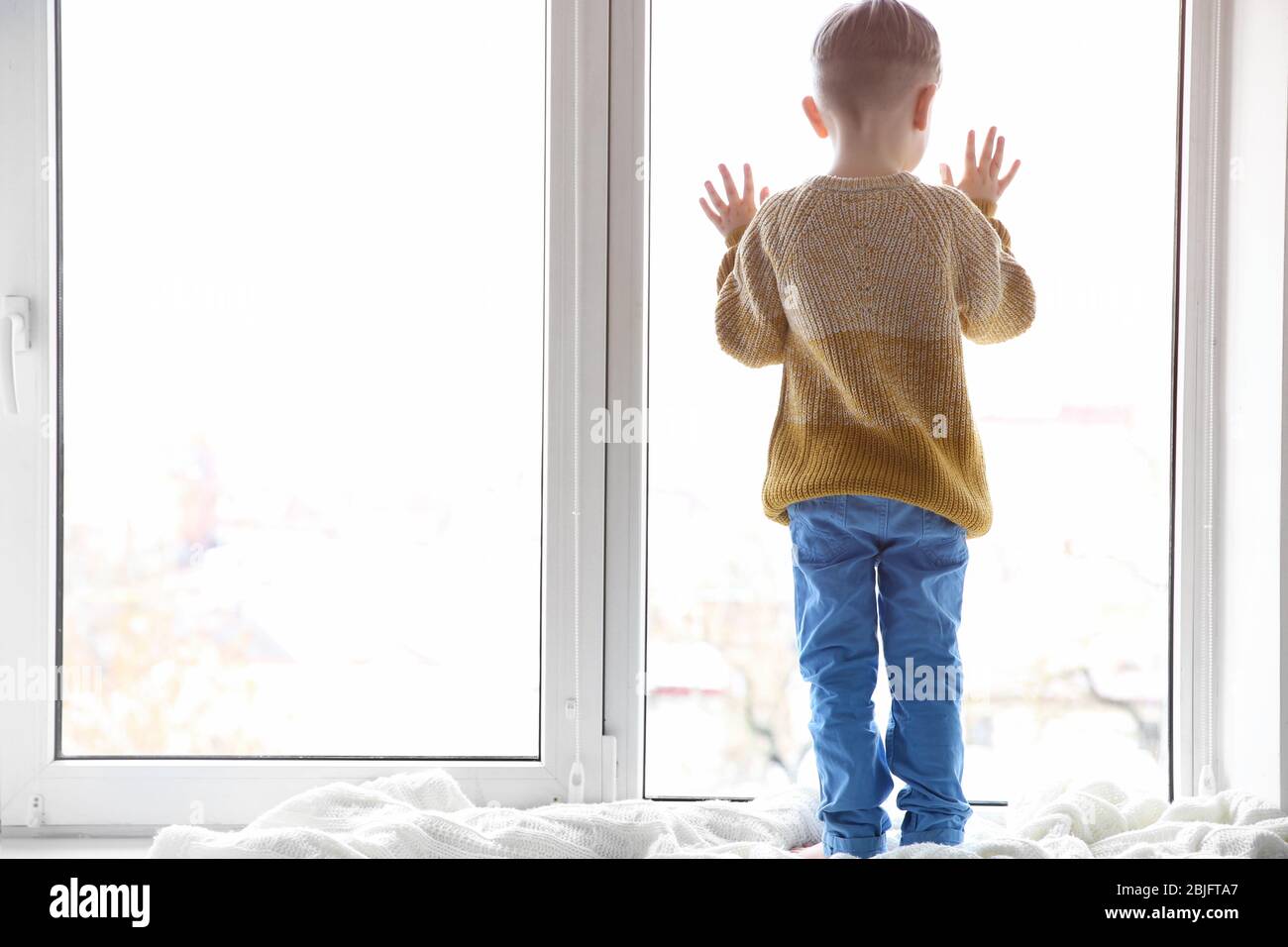 Cute little boy standing on windowsill Stock Photo - Alamy