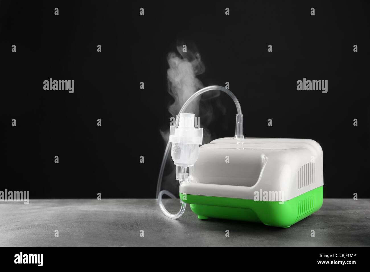 Compressor nebulizer on table against black background Stock Photo - Alamy