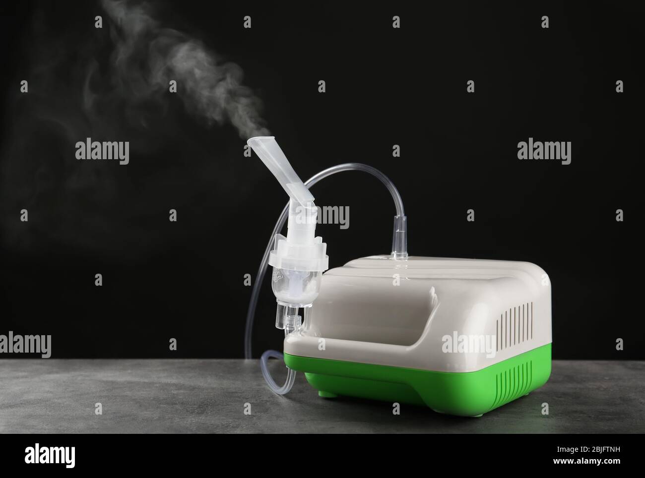 Compressor nebulizer with mouthpiece on table against black background ...