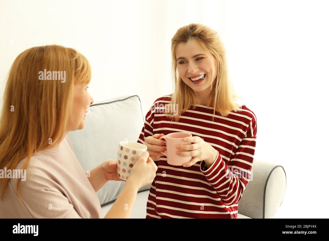 Happy young woman and her mother drinking tea at home Stock Photo - Alamy