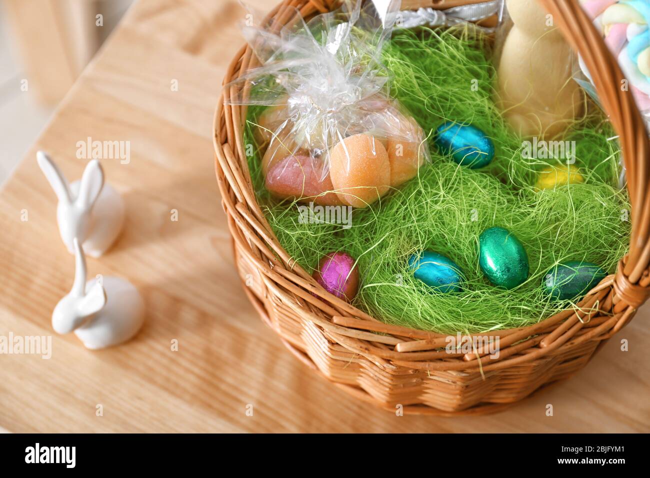 Easter presents in basket with decorative rabbits on wooden chair Stock ...