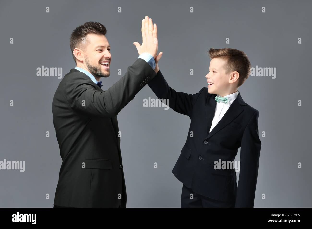 Father and son dressed in suits on color background Stock Photo - Alamy