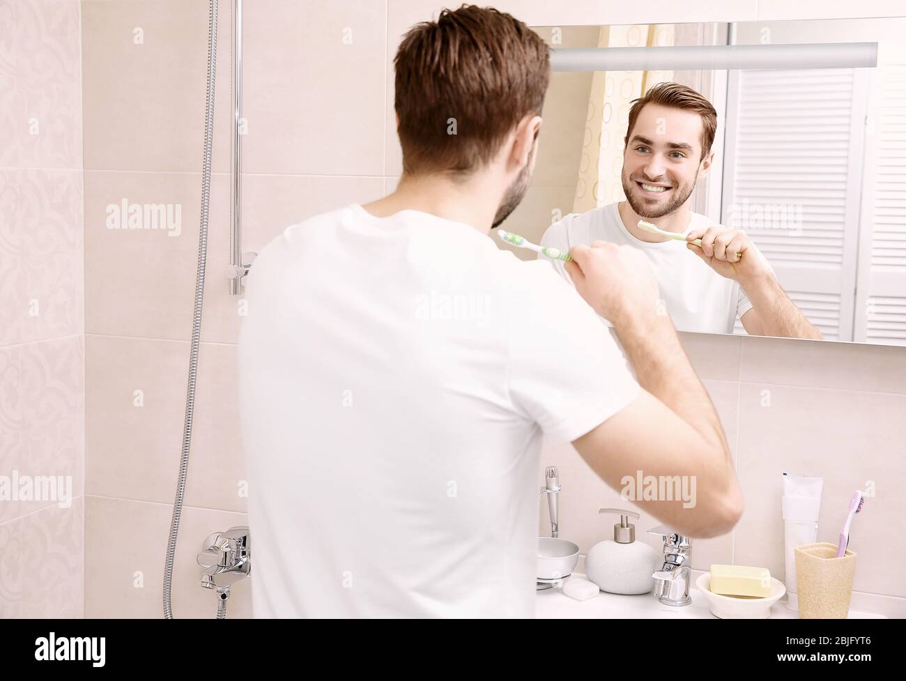 Handsome man brushing teeth in bathroom Stock Photo - Alamy