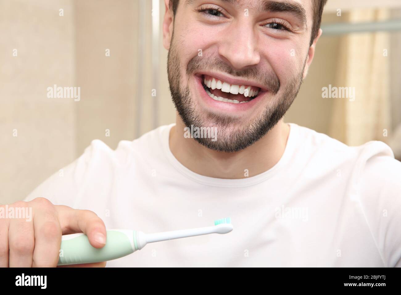 Handsome man brushing teeth in bathroom Stock Photo - Alamy