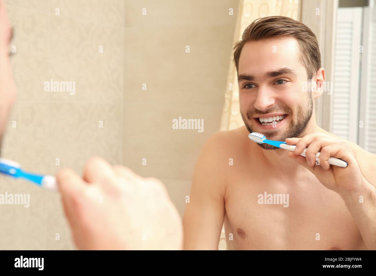 Handsome man brushing teeth in bathroom Stock Photo - Alamy
