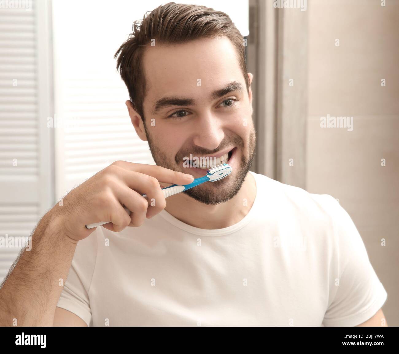 Handsome man brushing teeth in bathroom Stock Photo - Alamy