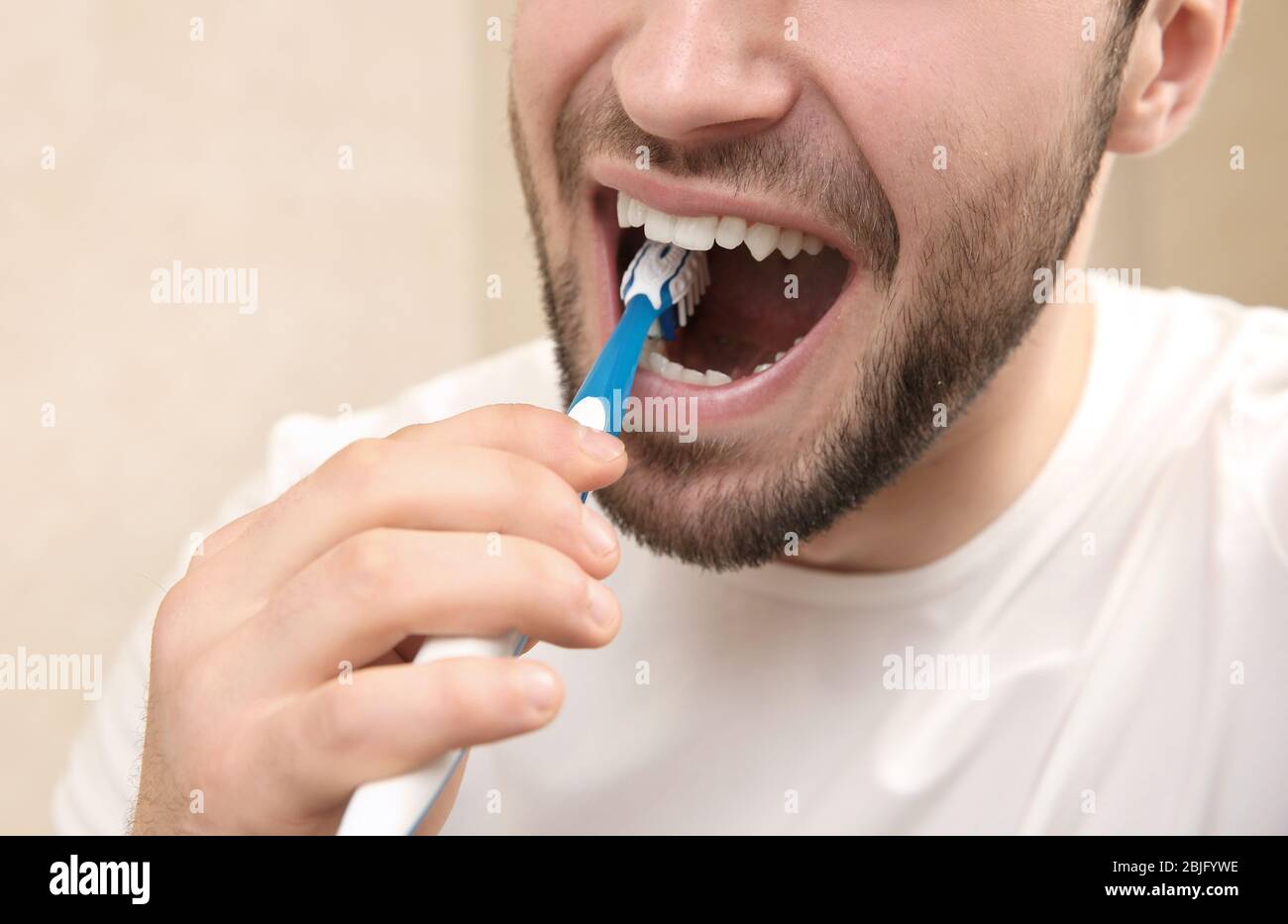 Handsome man brushing teeth in bathroom Stock Photo - Alamy